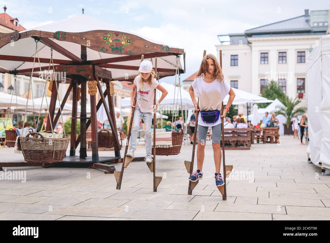 Two young girls walking on stelts during city festival, village fair ...