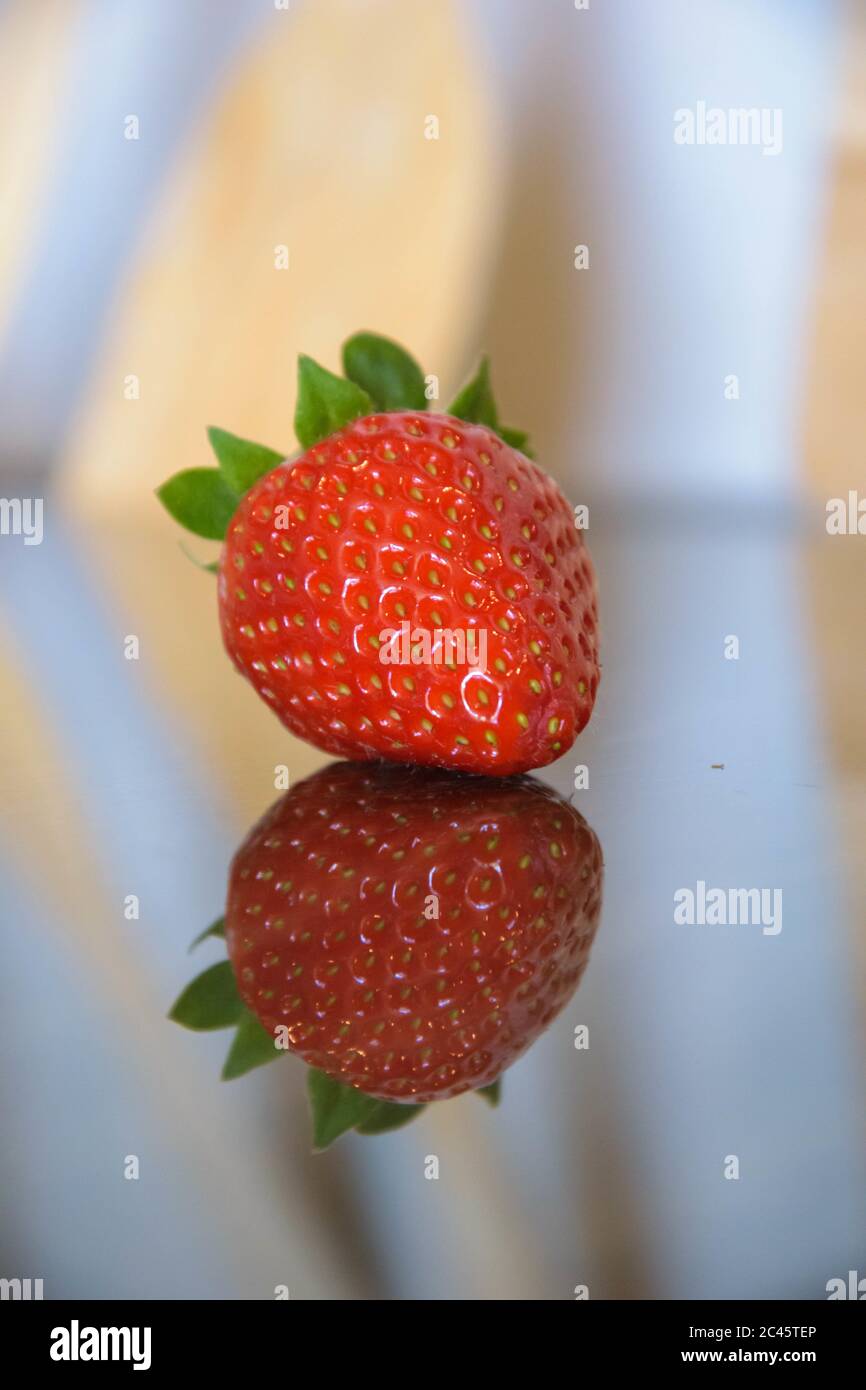 Vertical closeup shot of a fresh strawberry with a reflection on a ...