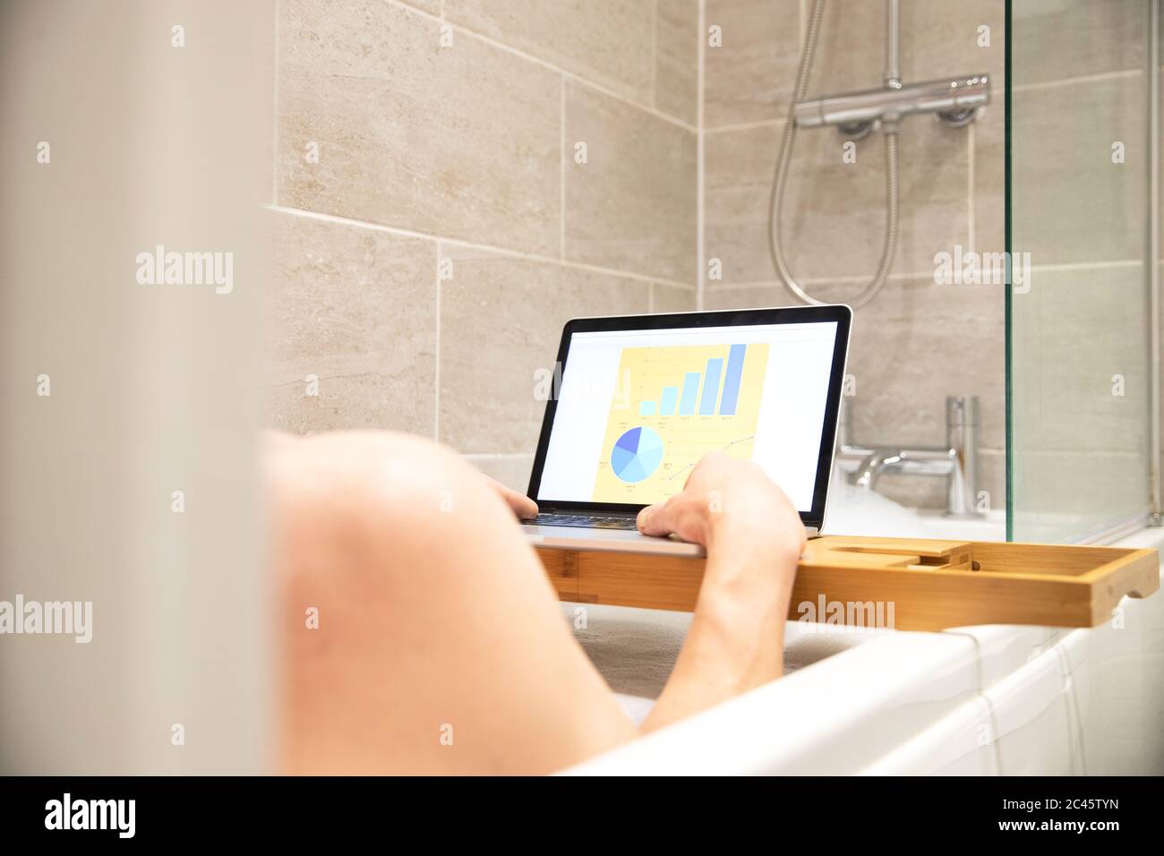 Woman sitting in bathtub, having foam bath and working on laptop during ...