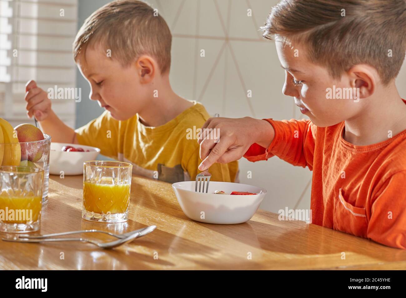 Two boys sitting at kitchen table, eating breakfast Stock Photo - Alamy