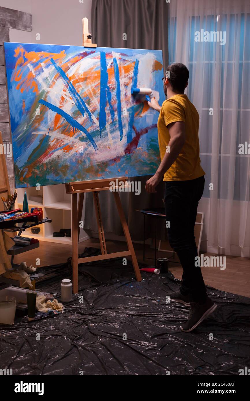 Creative artist painting with roller on canvas in art studio Stock ...