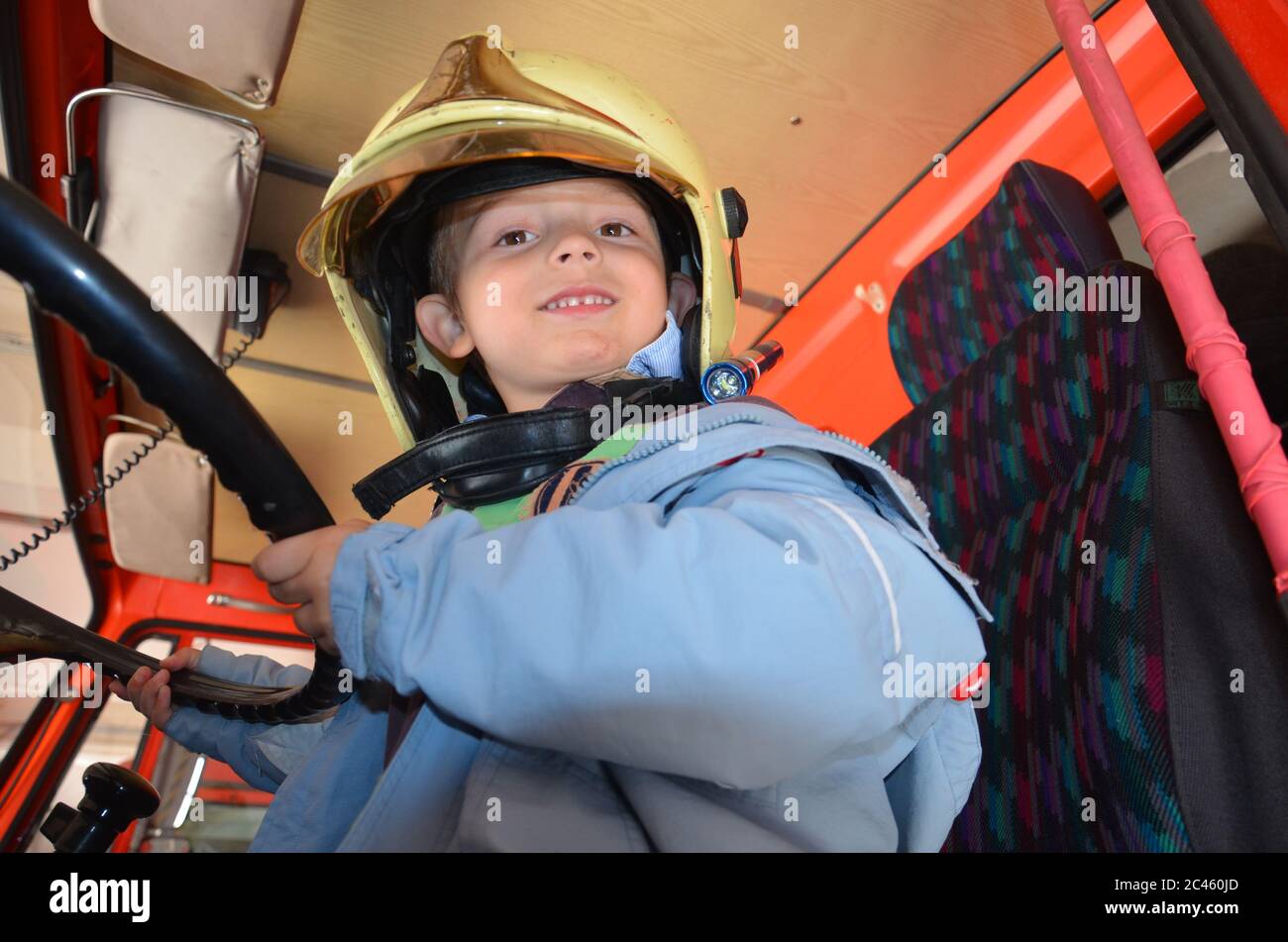 Little boy acting like a fireman. Boy sitting in a real fireman car ...