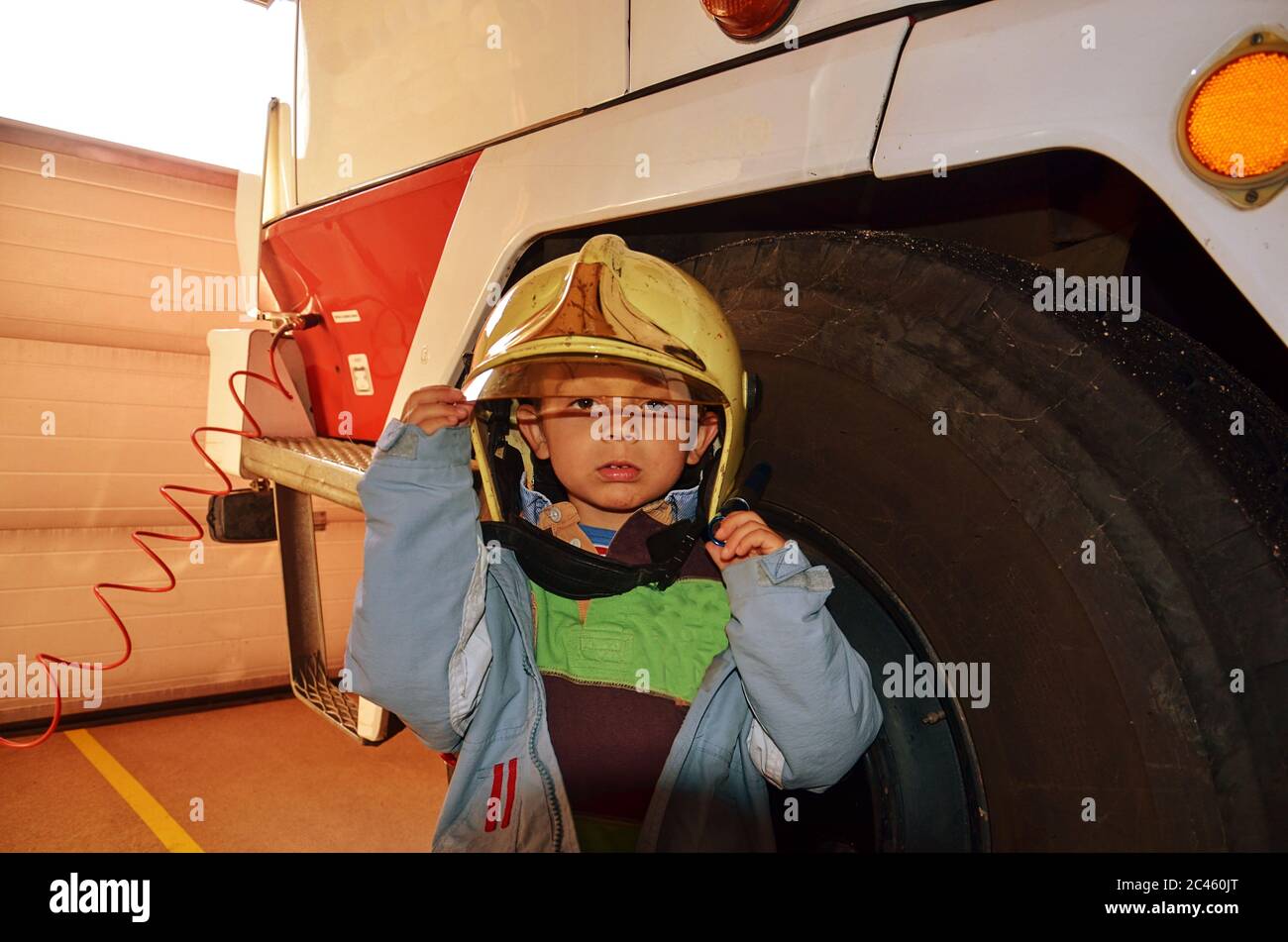 Little boy acting like a fireman. Boy standing next a real fireman car ...