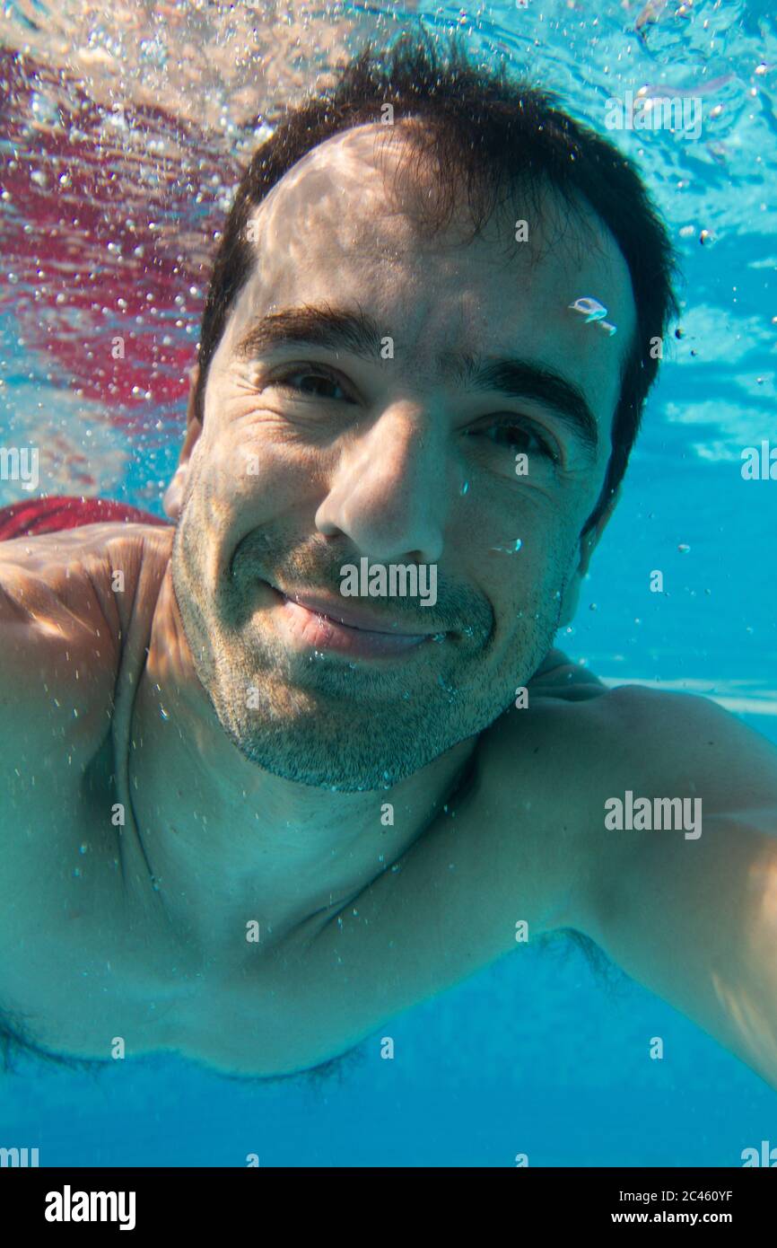 A man swimming underwater, smiling at a camera, an underwater selfie ...