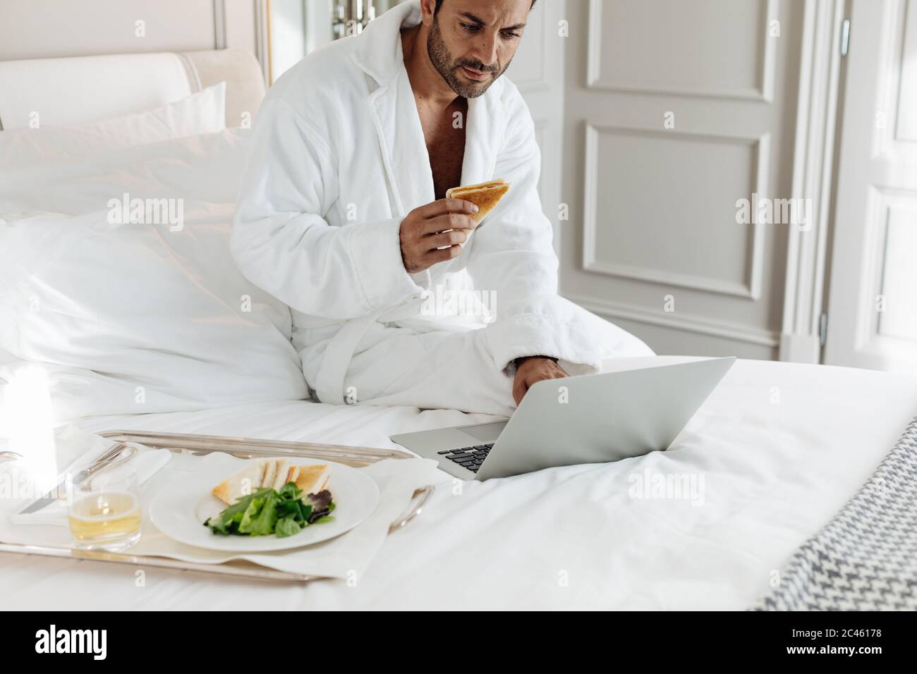 Man using laptop and having toast in suite Stock Photo - Alamy