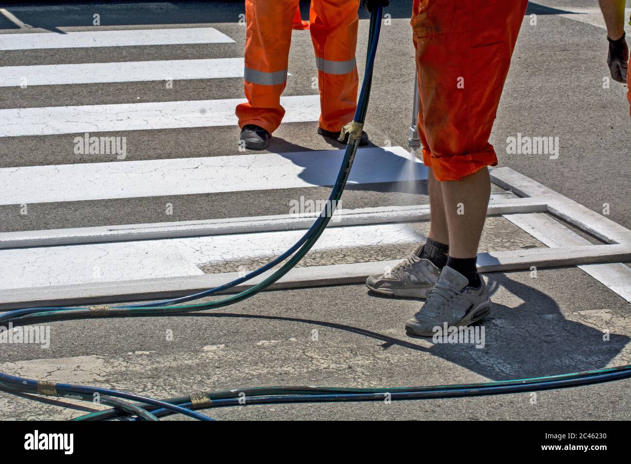 Workers are painting a pedestrian crossing in a city street Stock Photo ...