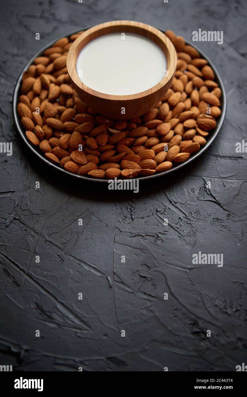Composition of almonds seeds and milk, placed on black stone background ...