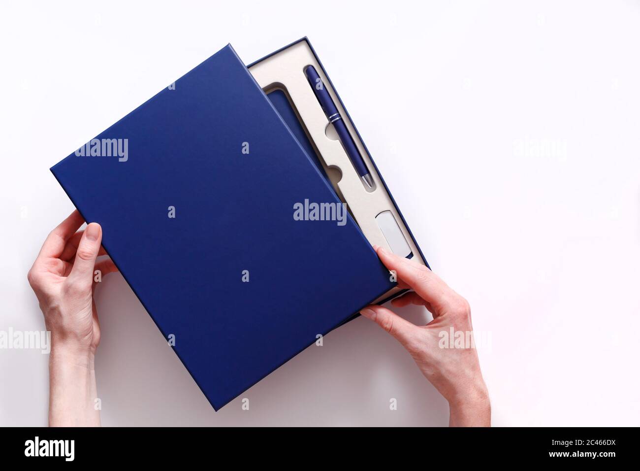 Woman hands open cover of corporate style box with pen, flash drive and ...