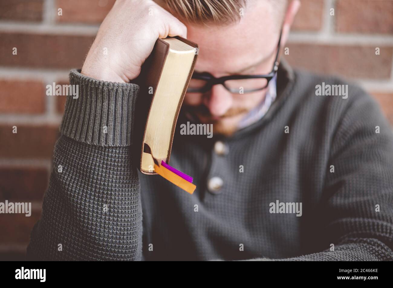 Sad man holding a book with closed eyes Stock Photo - Alamy
