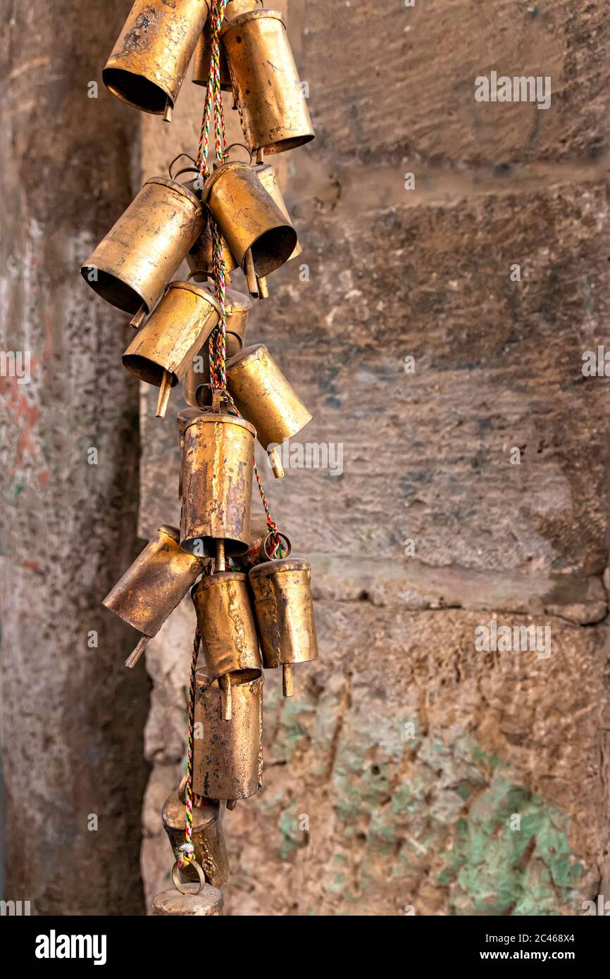A bunch of copper bells on a multi-colored thread close-up on a stone ...