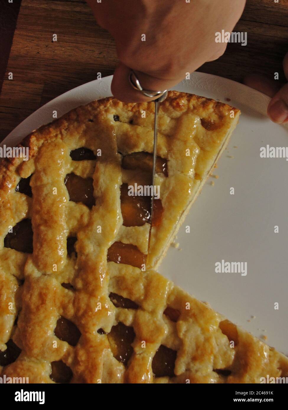 Vertical closeup shot of a female hand cutting linzer torte Stock Photo ...