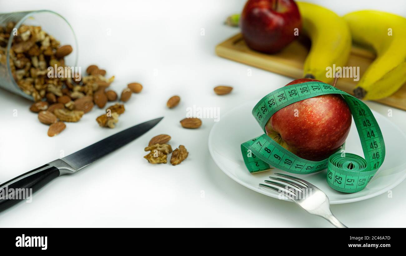 An Apple, a tape measure, nuts, and placed on a white background remind ...