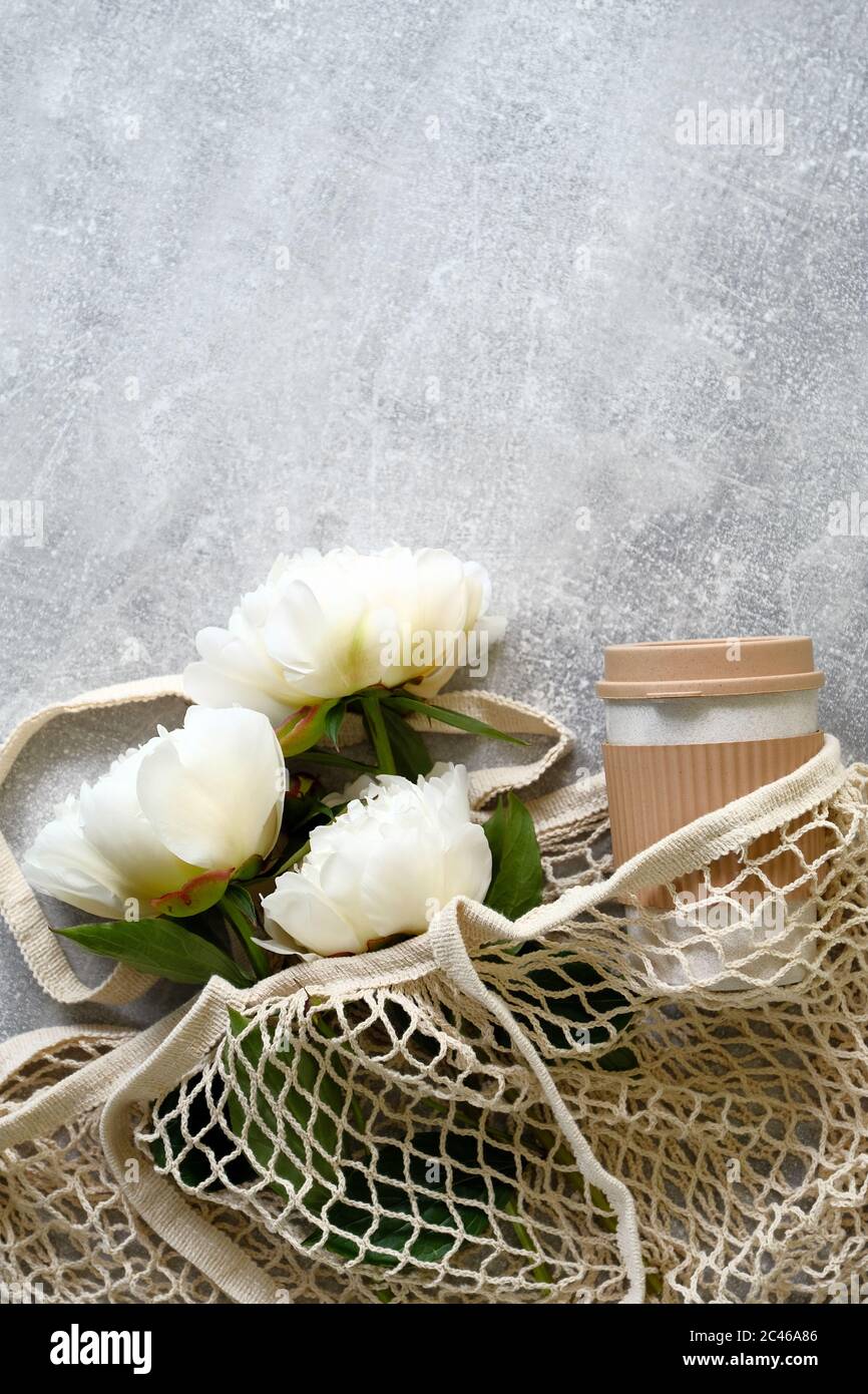 Eco friendly string bag with peony flowers and bamboo coffee cup on ...