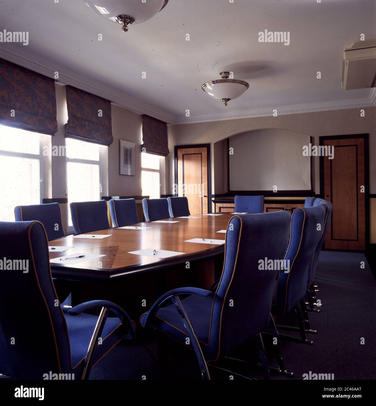 Wooden boardroom table surrounded by blue upholstered chairs Stock ...