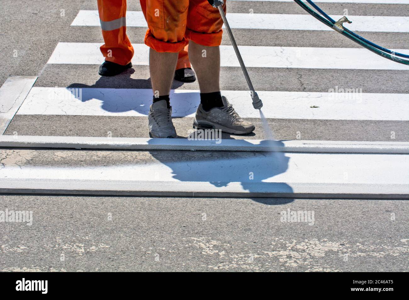 Workers are painting a pedestrian crossing in a city street Stock Photo ...