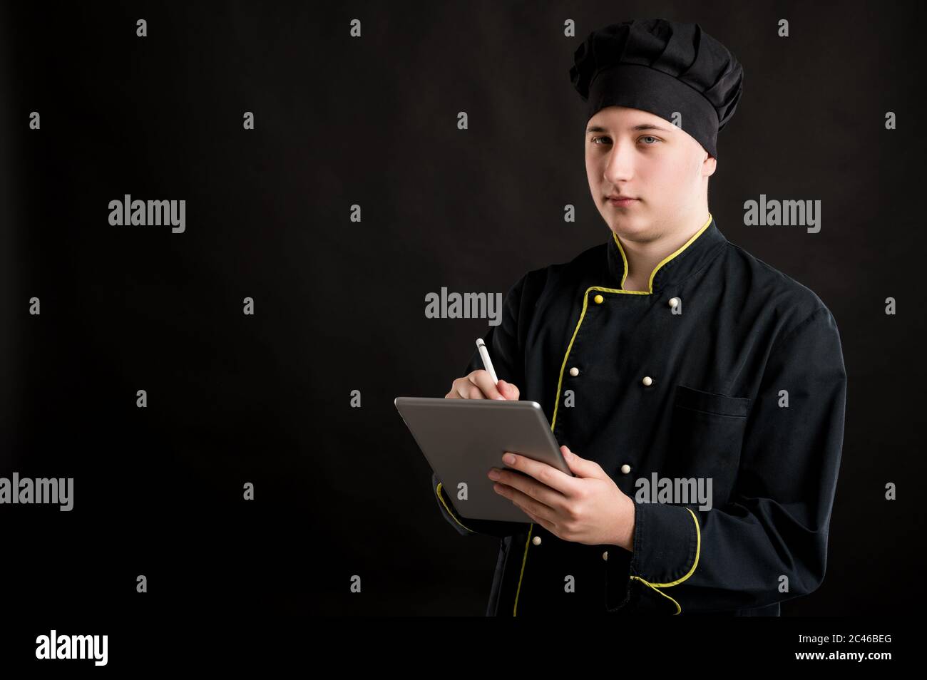 Portrait of young male dressed in a black chef suit takes notes ...