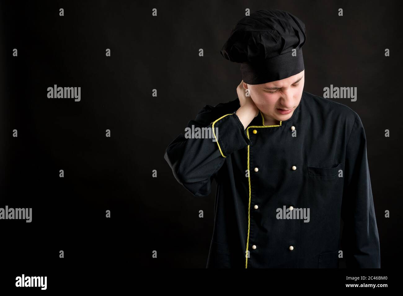 Portrait of young male dressed in a black chef suit with open arms ...