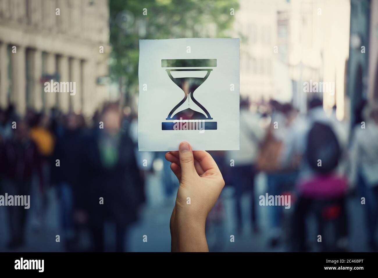 Business time concept. Human hand holds a paper sheet with an hourglass ...