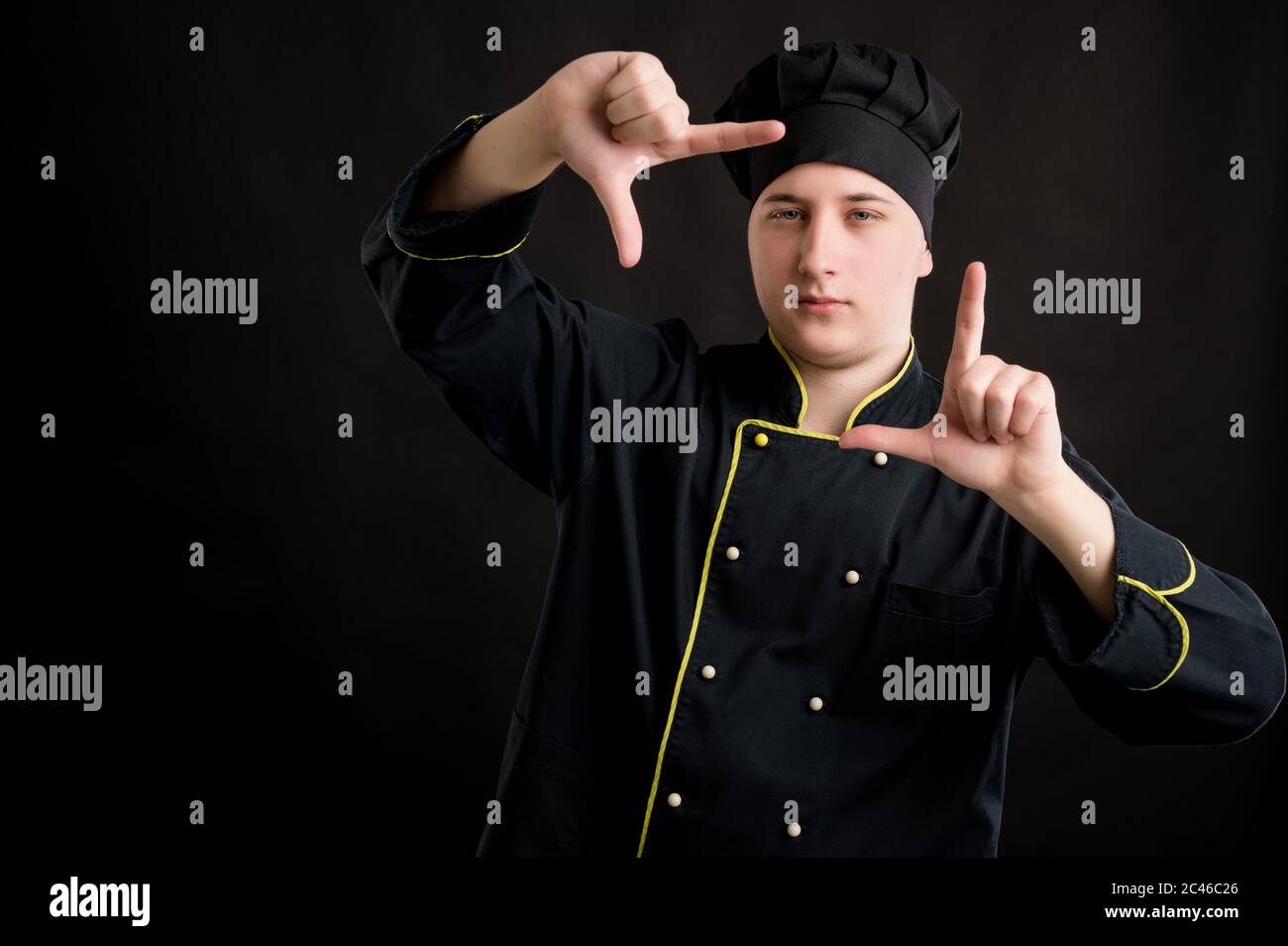 Portrait of young male dressed in a black chef suit frameing posing on ...