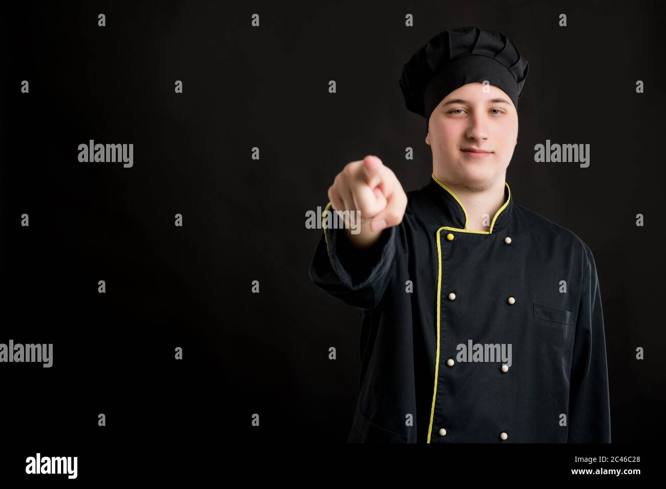 Young male dressed in a black chef suit smileing and pointing his ...
