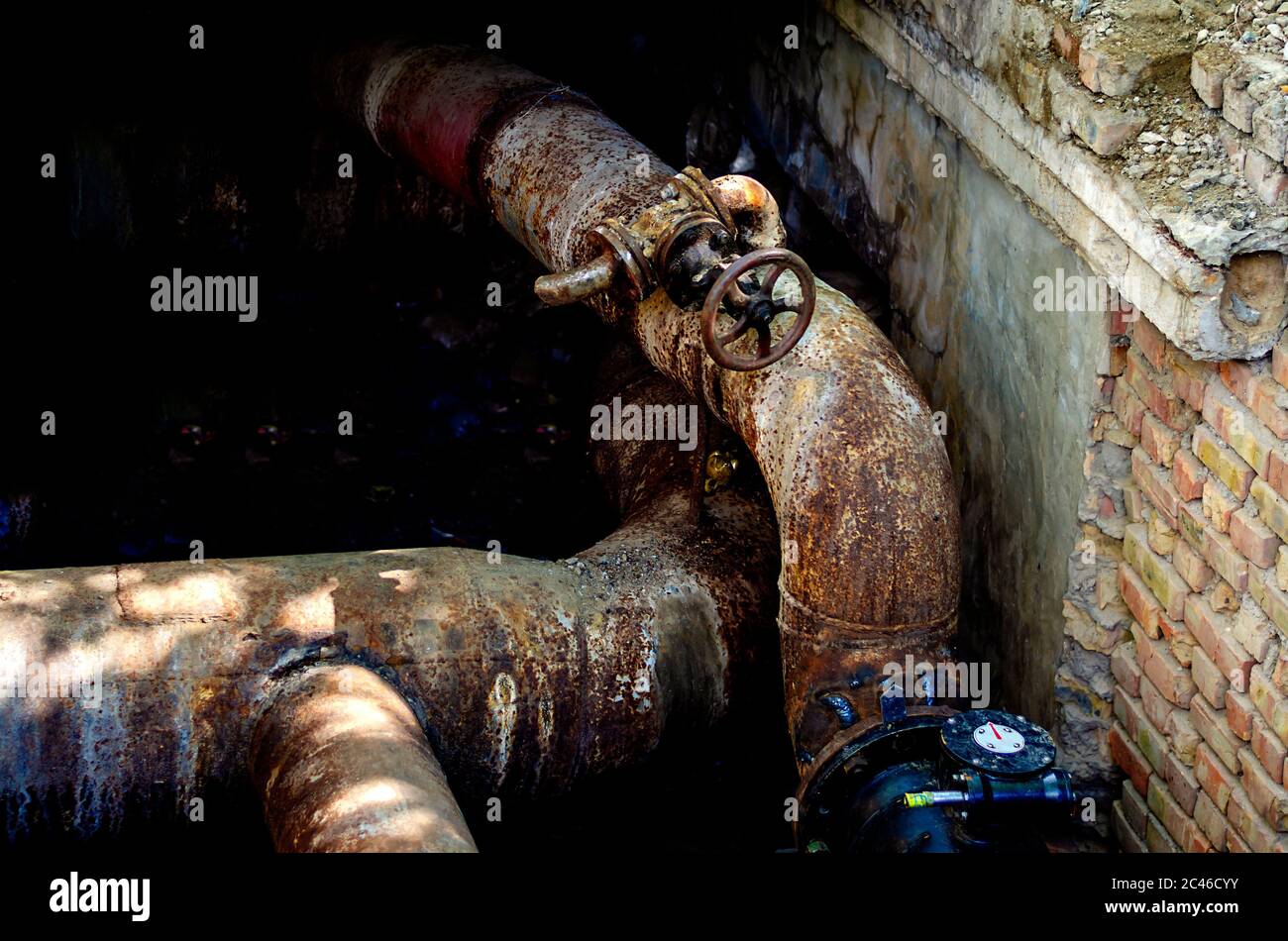 An open underground pipeline with valves in a brick well. Underground ...