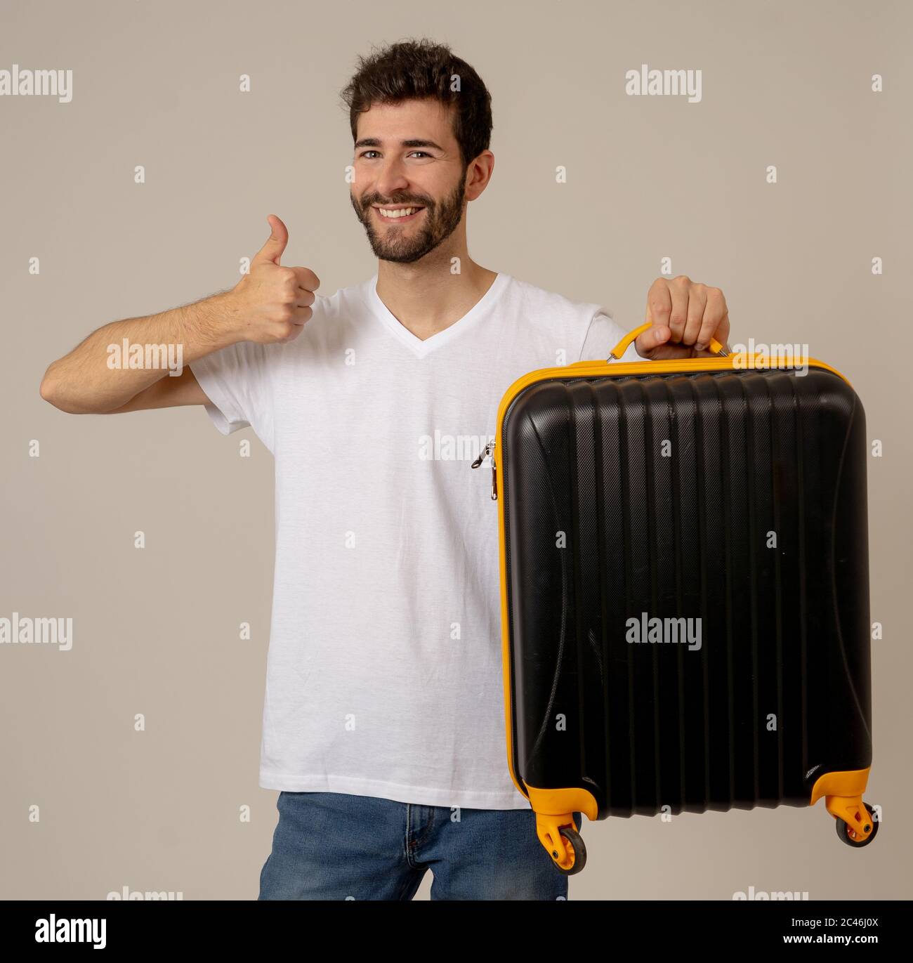 Attractive young traveler man showing suitcase isolated on neutral ...