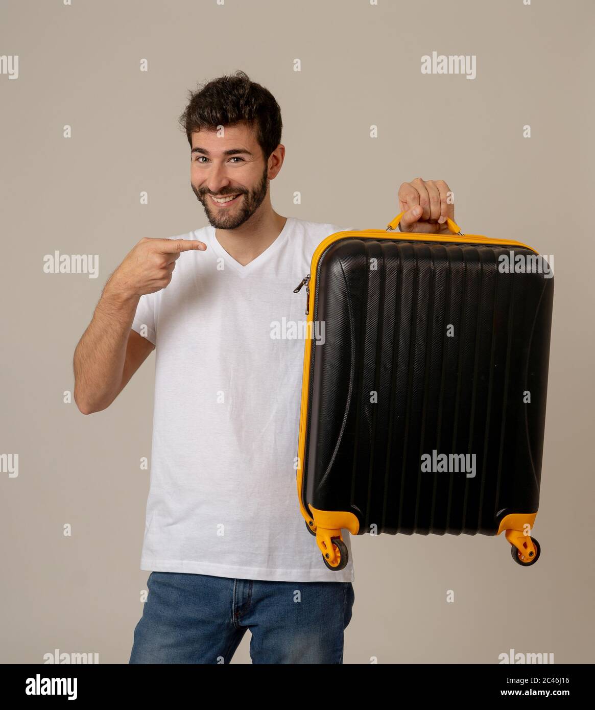 Attractive young traveler man showing suitcase isolated on neutral ...