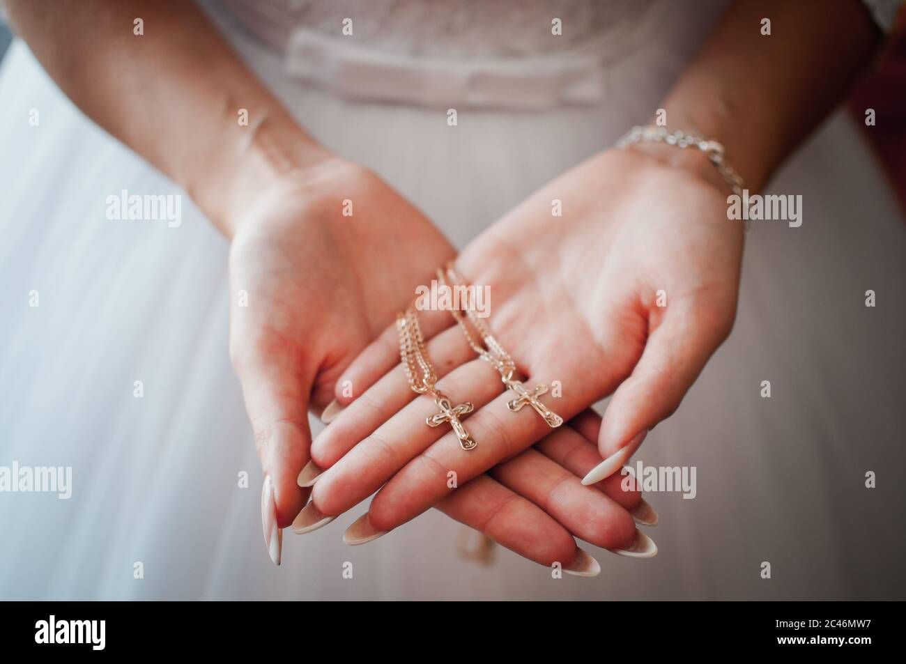 Bride holding gold christian crests in the hands Stock Photo - Alamy