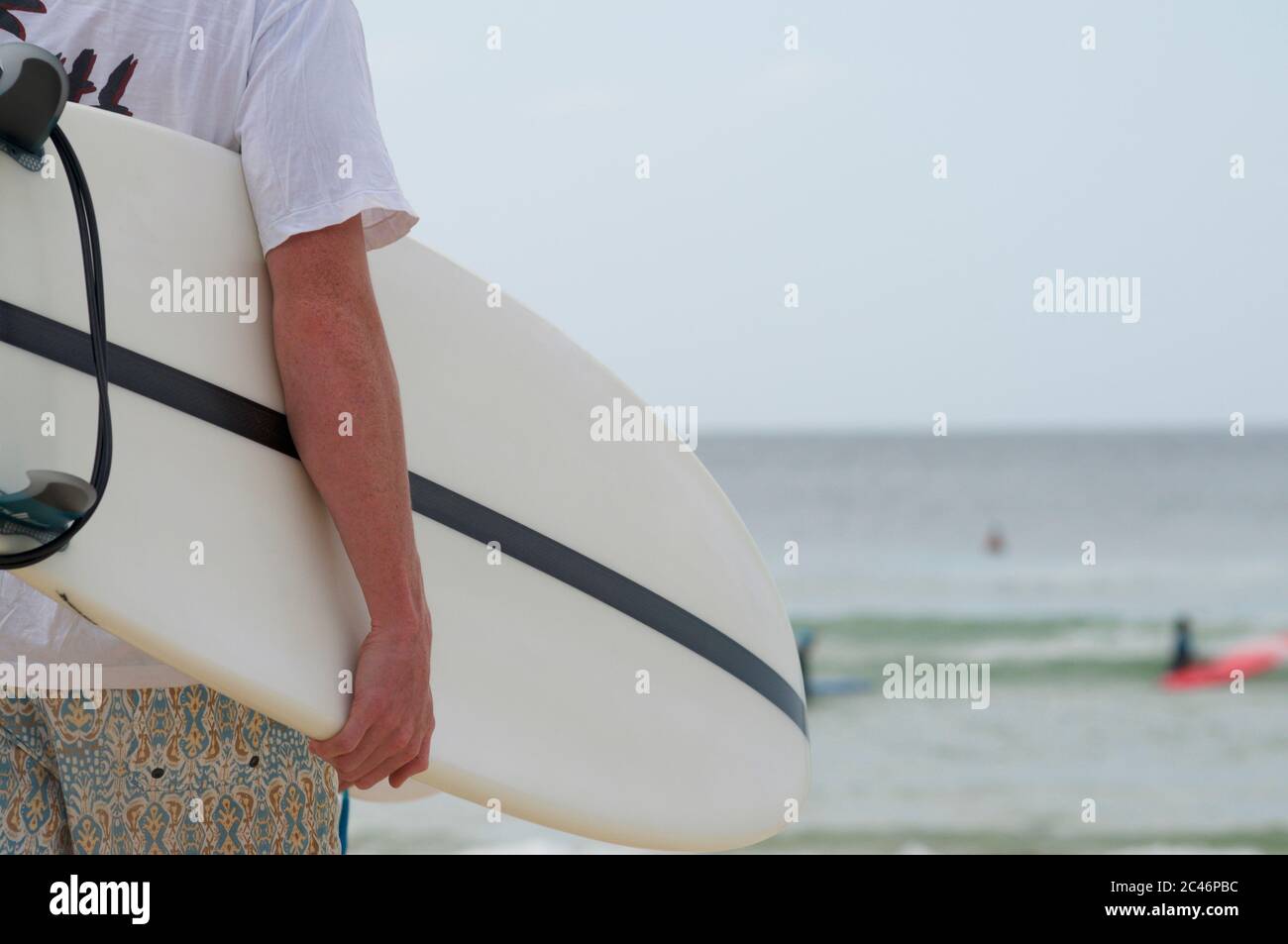 Rear view of a man holding a surfboard by standing in front of the ...