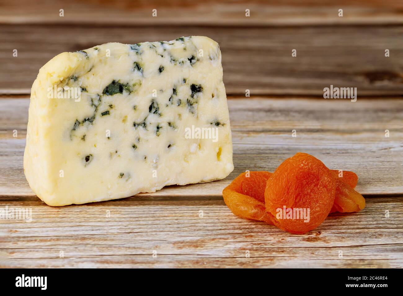 Blue stilton England cheese with dried apricots on wooden background ...