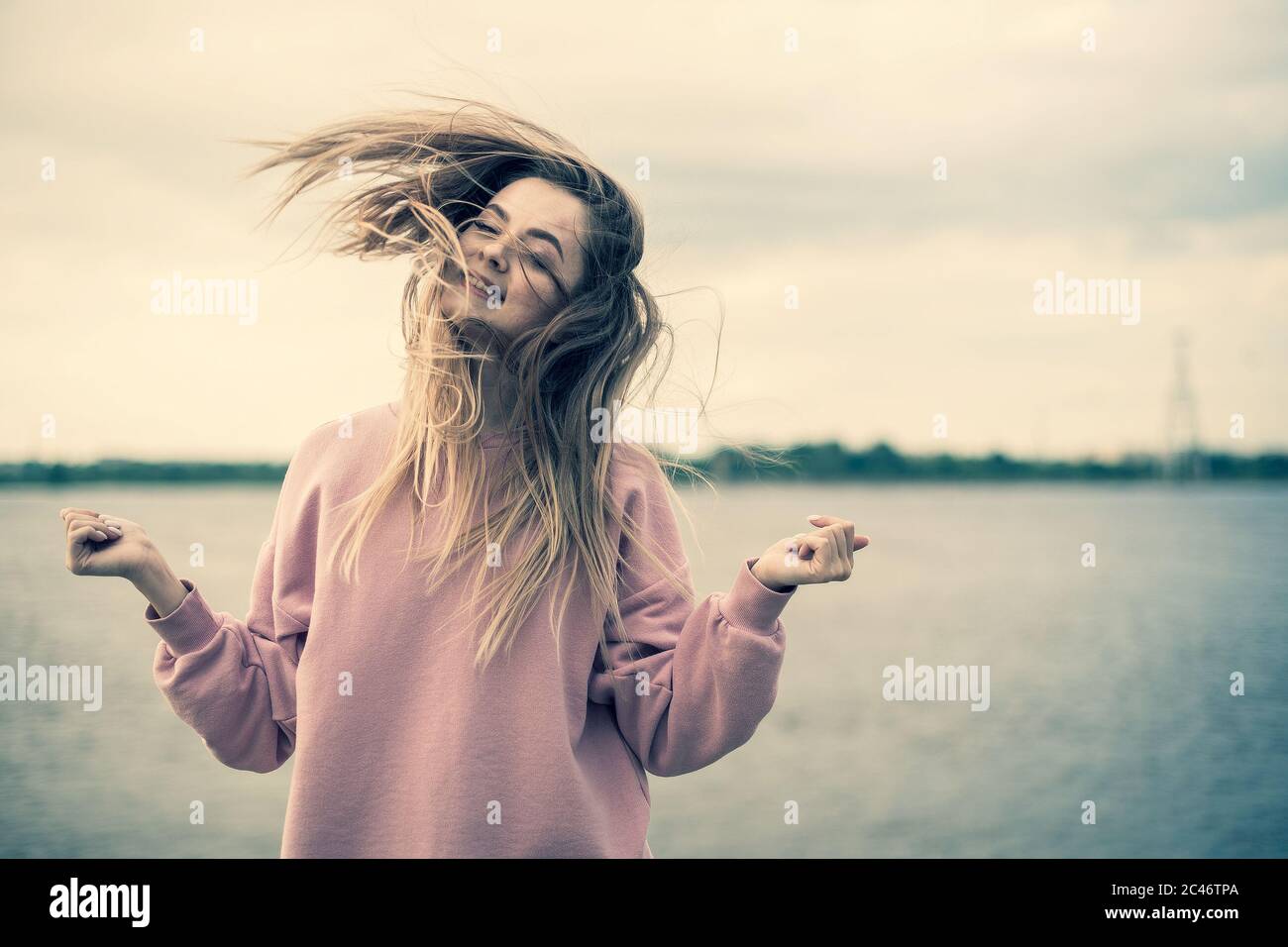 A young positive girl with a happy smile plays with the wind with her ...
