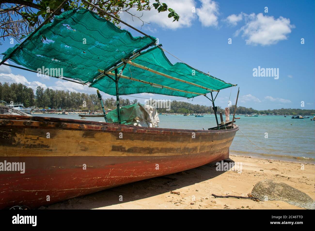 Secluded beach local fishing boat on sand framed by trees turquoise sea ...