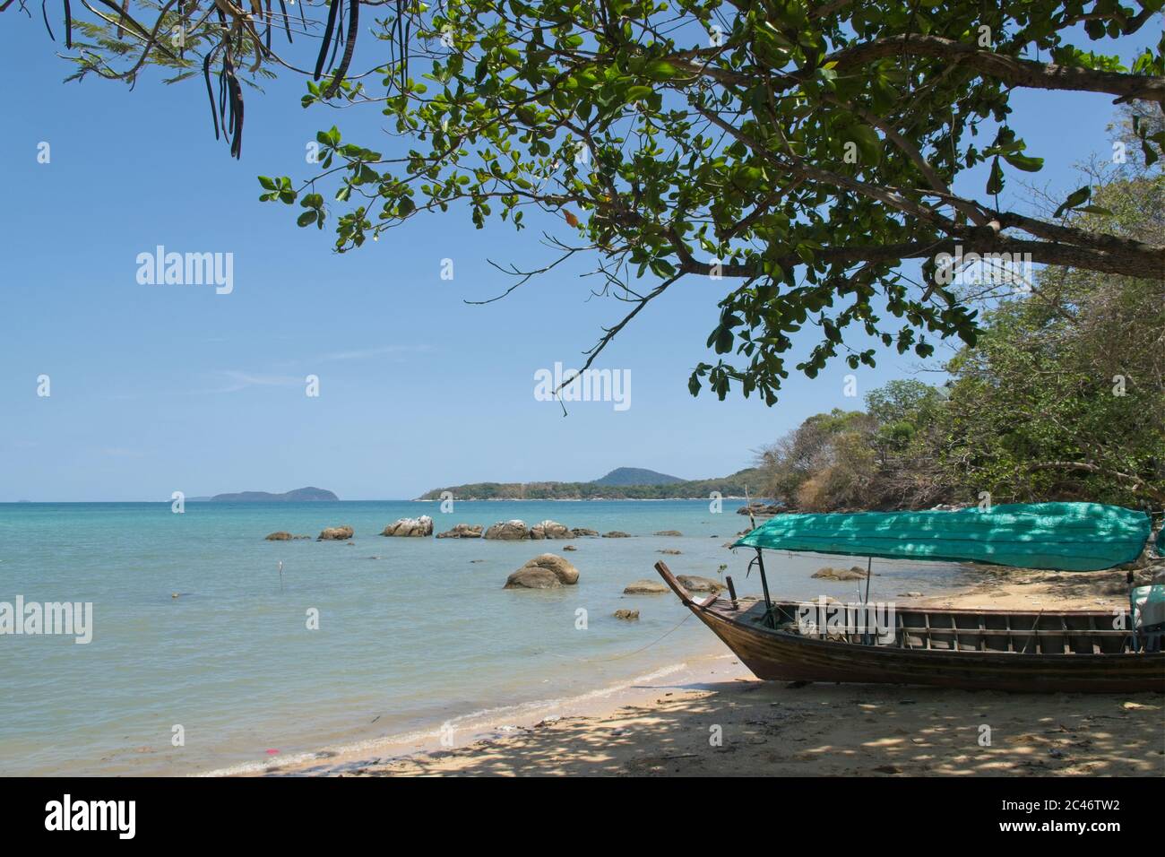 Secluded beach local fishing boat on sand framed by trees turquoise sea ...