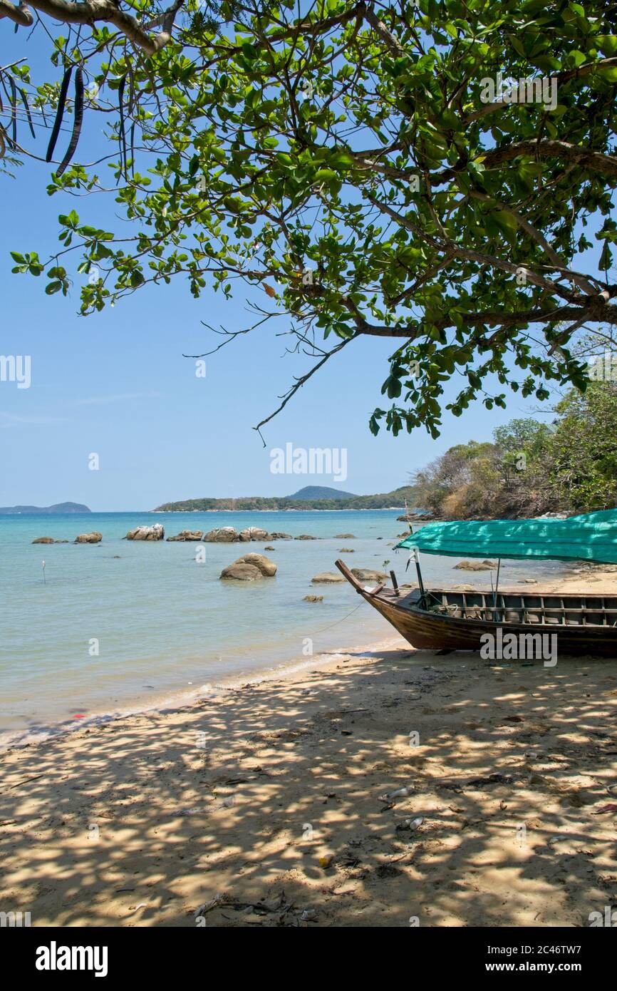 Secluded beach local fishing boat on sand framed by trees turquoise sea ...