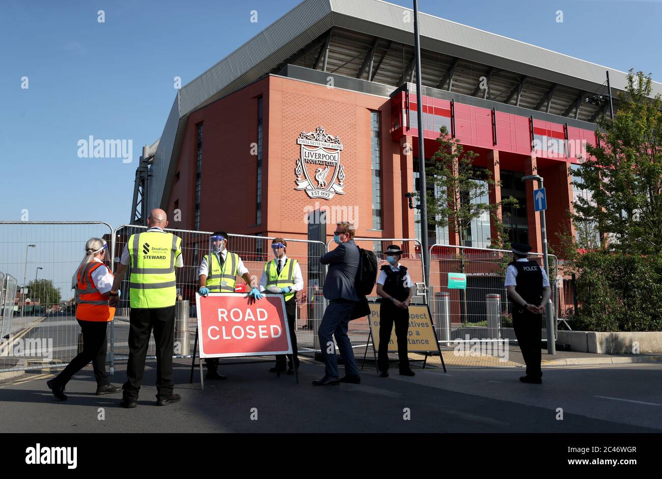 Stewards and police wearing PPE equipment close off the road outside ...