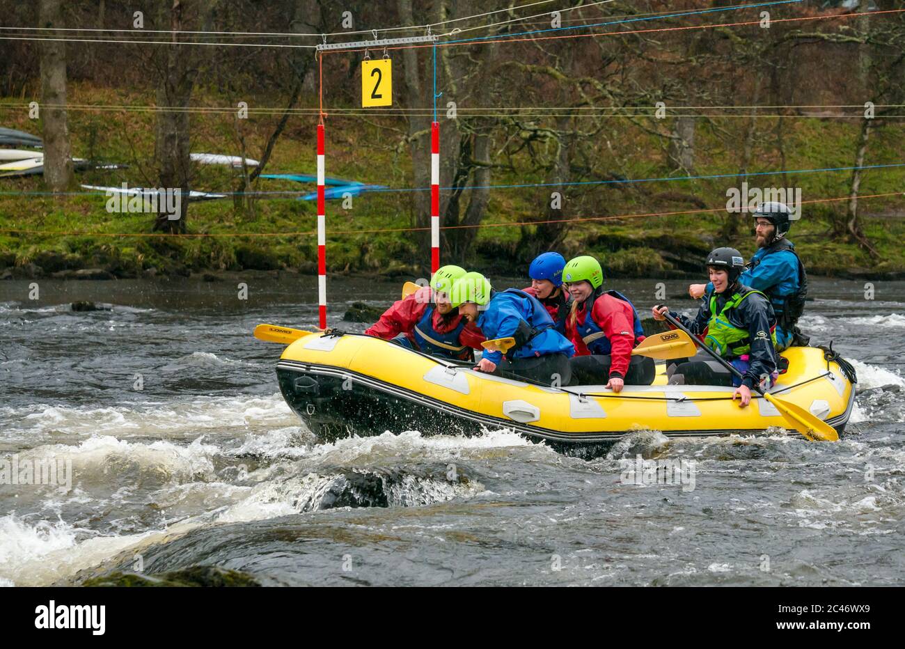 People in rubber raft going down rapids with canoe slalom posts ...