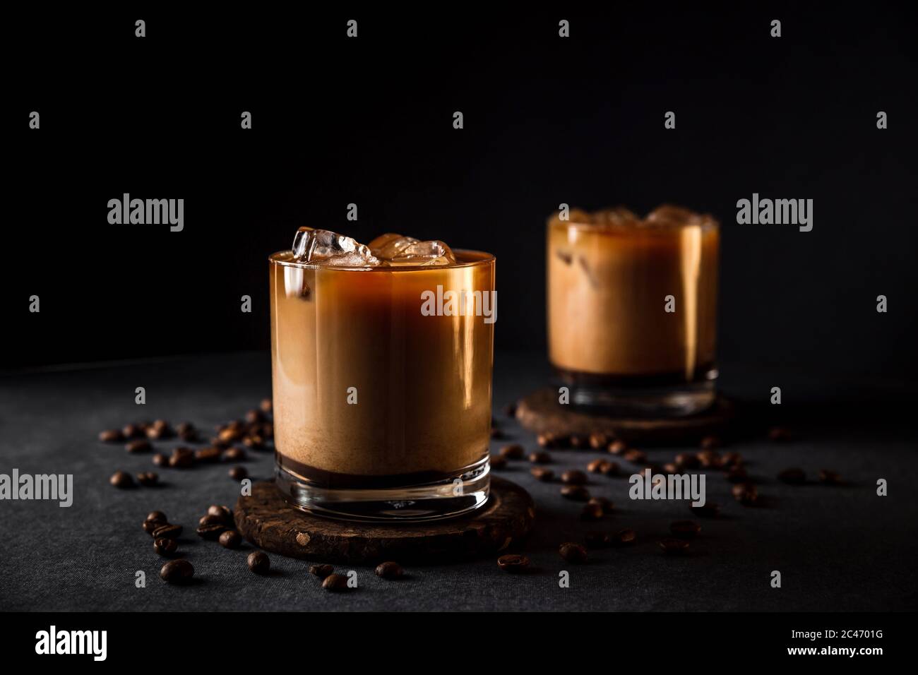 A horizontal photo of 2 rocks glasses with cold iced coffee with milk ...