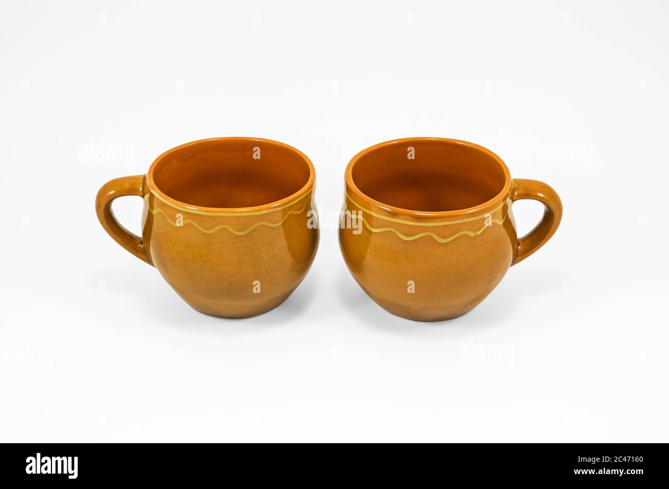 Two empty homemade clay cups of orange color isolated on white ...