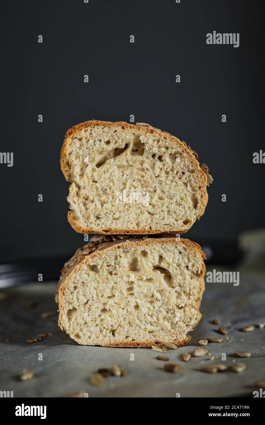 A homemade bread cut in half, one half on top of another, covered in ...