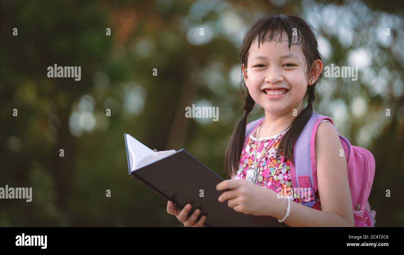 Happy school girl reading book with backpack.Back to school concept ...