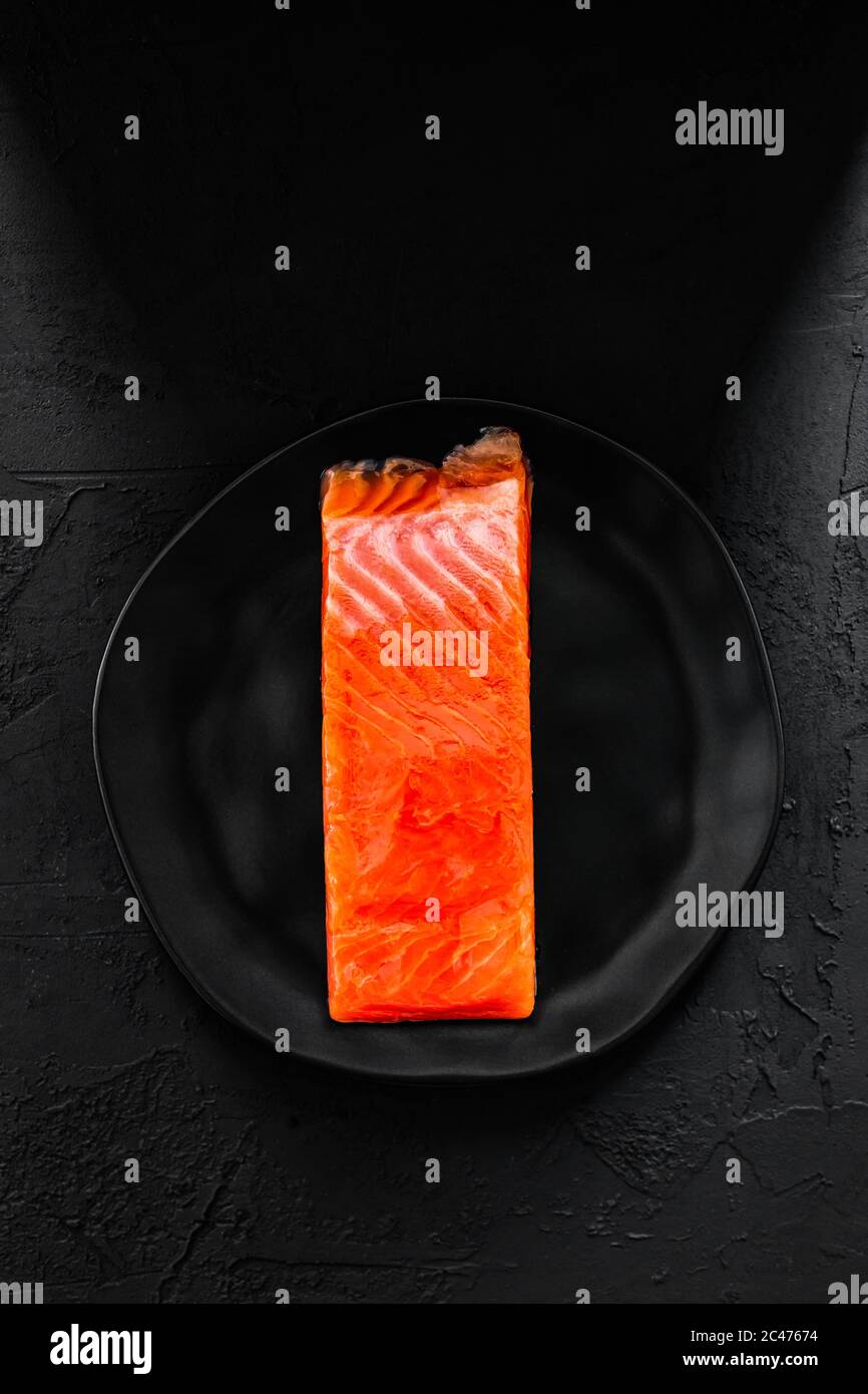 Salted red fish on a black plate on black background, top view vertical ...