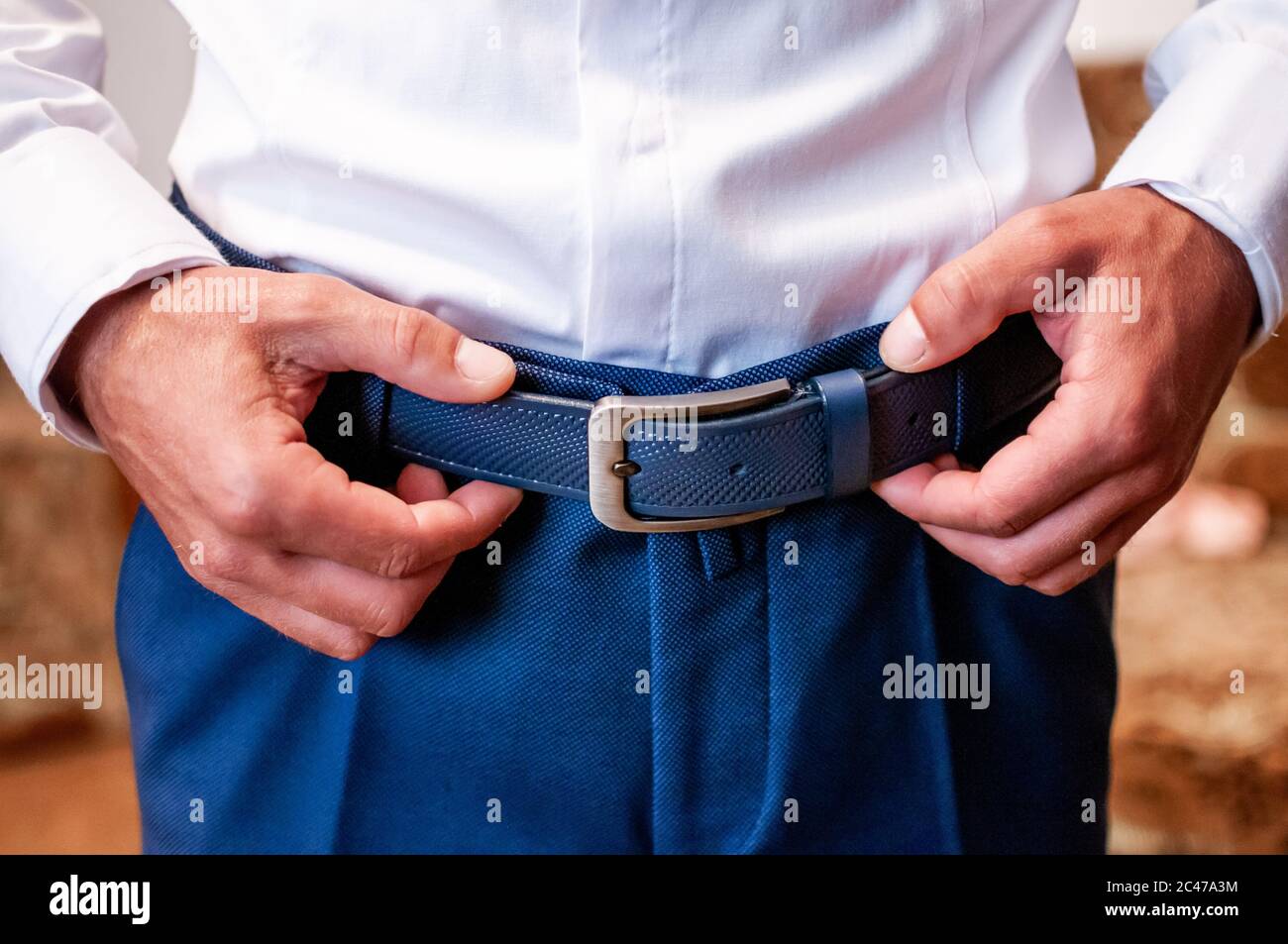 Groom holding hands on belt Stock Photo - Alamy