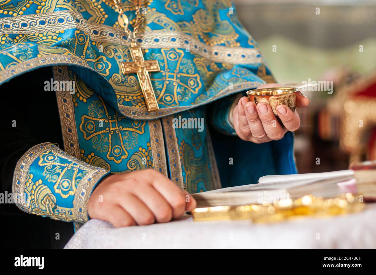 Priest holding silver chalice with wine Stock Photo - Alamy