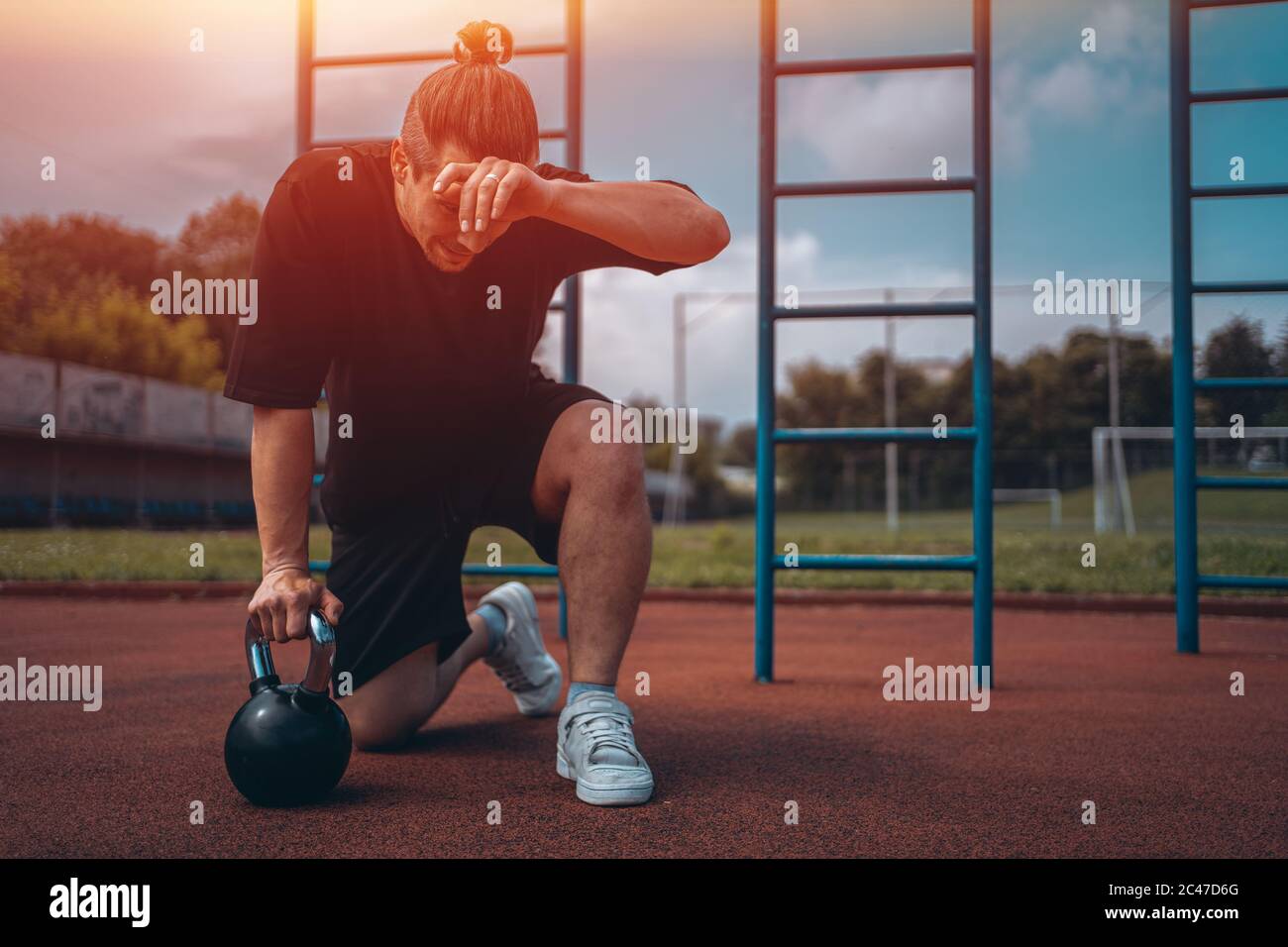 exhausted man athlete taking break between exercising with kettlebell ...