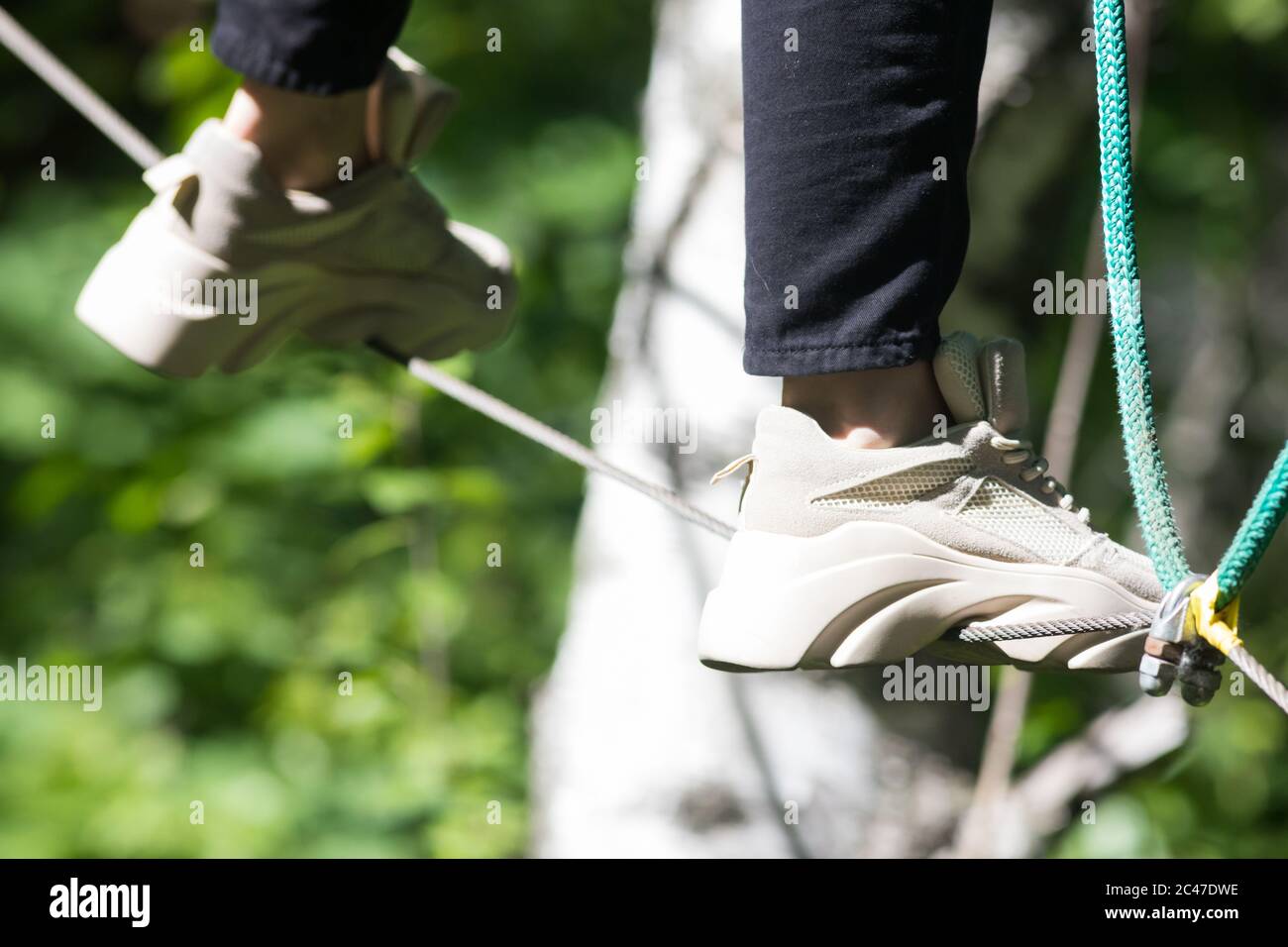 Rope adventure - woman in sneakers carefully walks on the rope. Mid ...