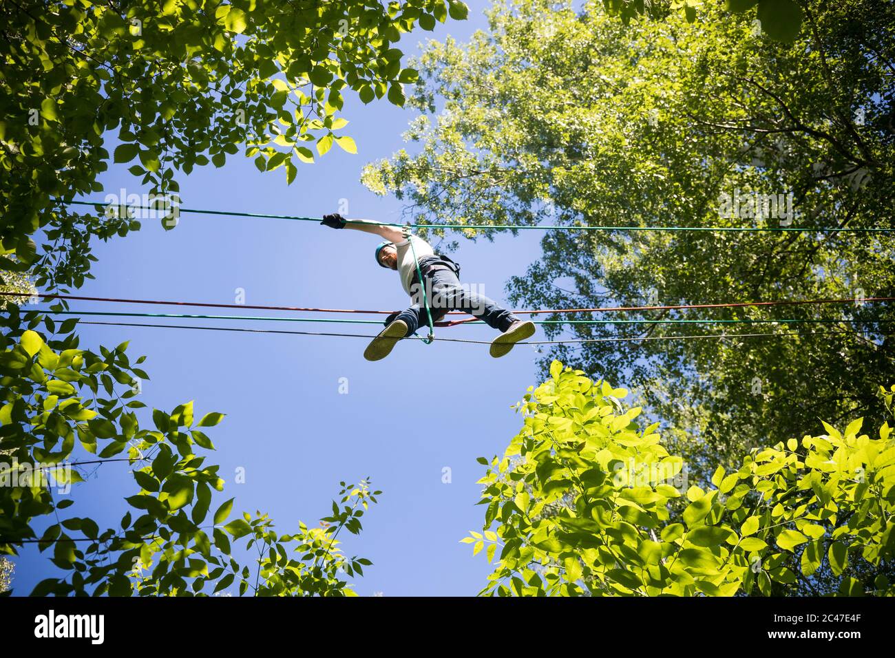 Rope adventure - man walking across the rope between two stands. Mid ...