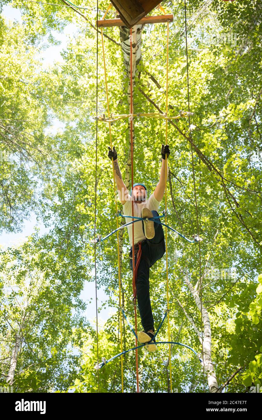 Rope adventure - man crossing the rope bridge on high. Mid shot Stock ...