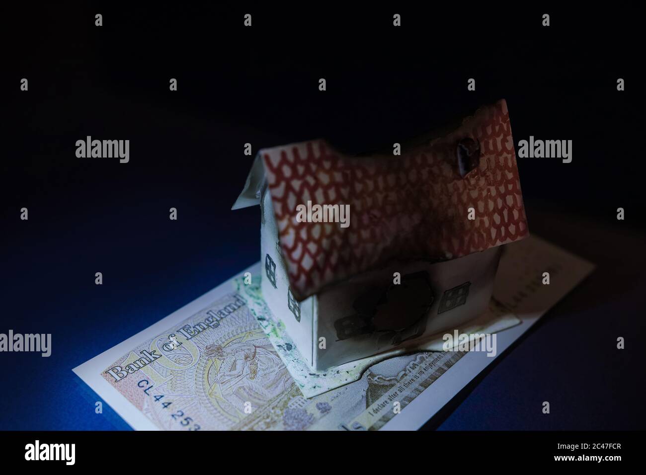 A cardboard model house, partially destroyed by fire, placed on a ...