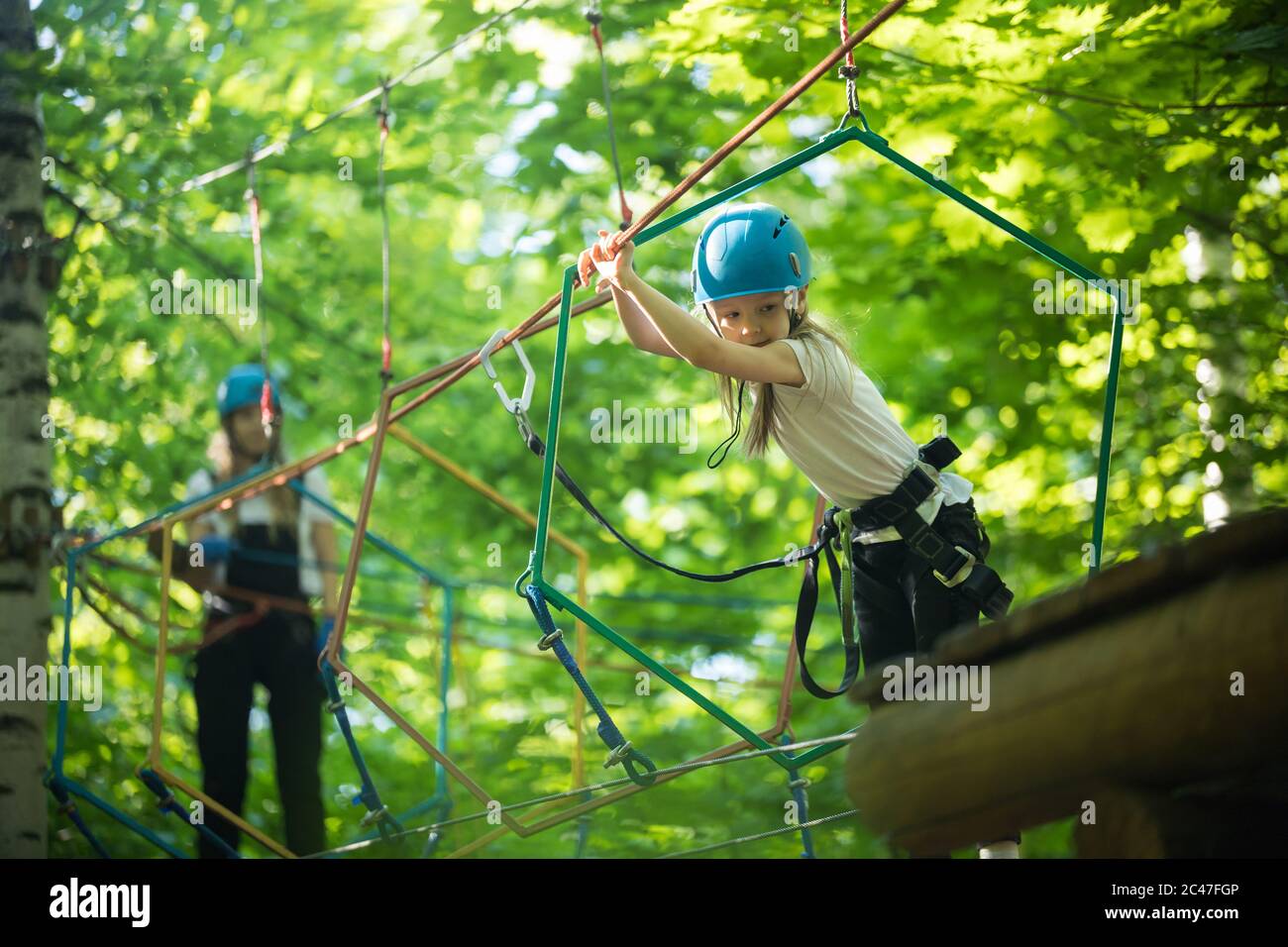 Rope adventure - a little girl walks on the rope bridge to the stand ...