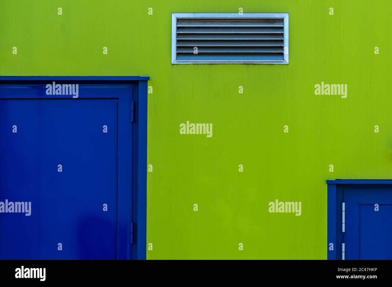 Horizontal shot of a white air vent and two blue doors on a bright ...